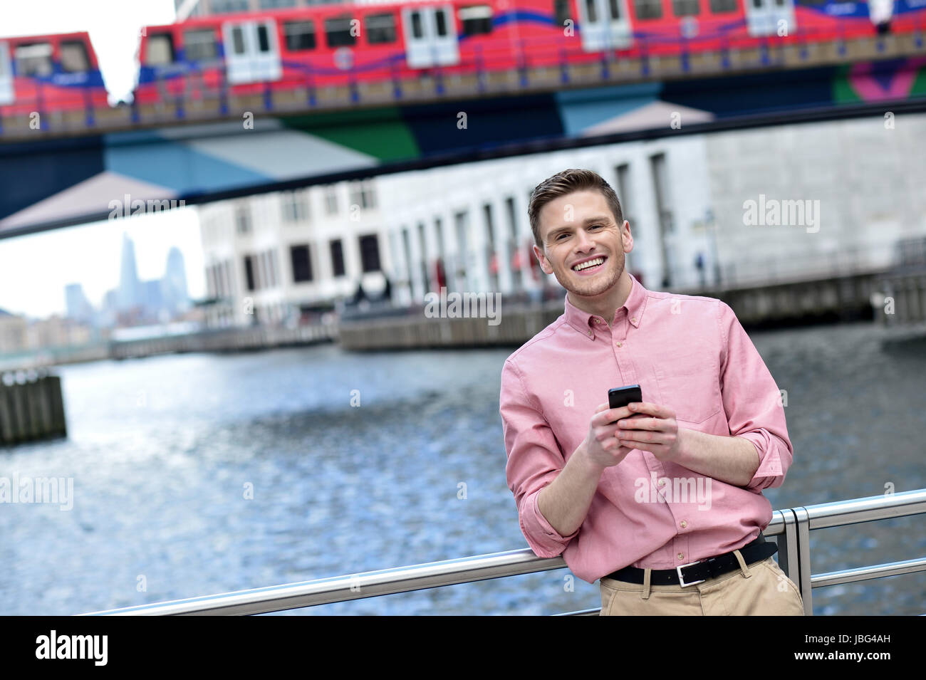 Young man texting through mobile phone at bridge railing Stock Photo ...