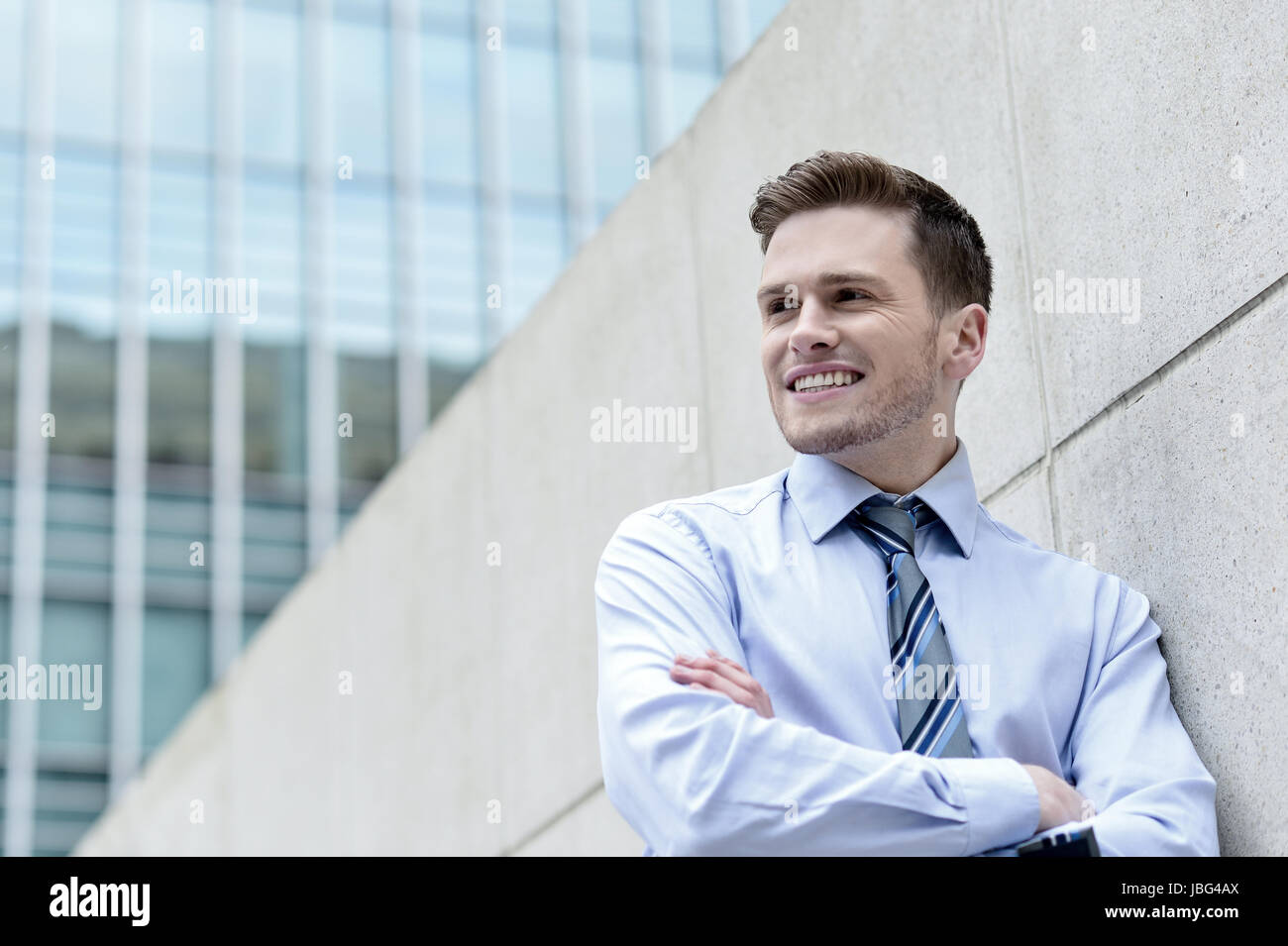 Young business man leaning against the wall, arms crossed Stock Photo - Alamy