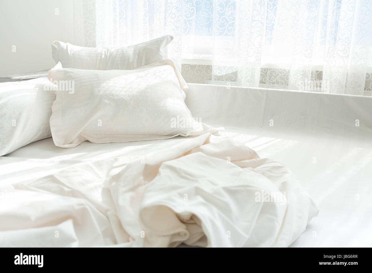 Photo of untidy bed against window Stock Photo - Alamy
