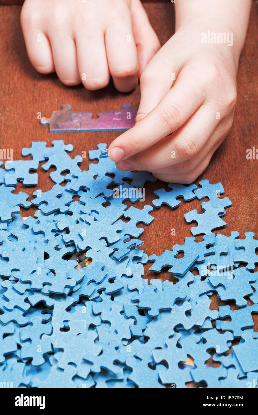 assembling of jigsaw puzzles on wooden table Stock Photo - Alamy