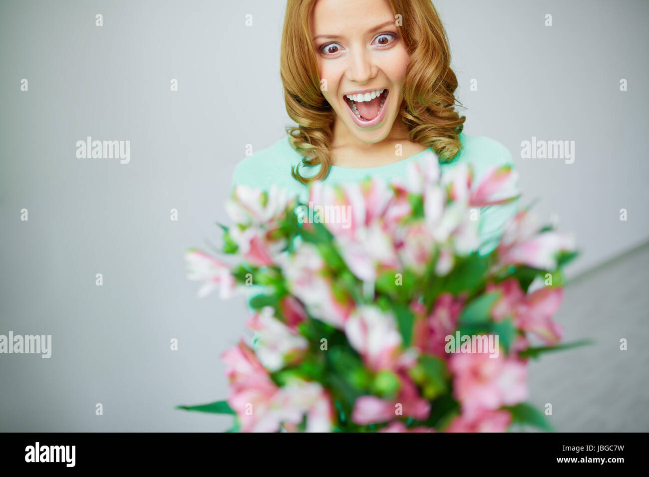 Portrait of ecstatic woman with bunch of flowers looking at it with ...