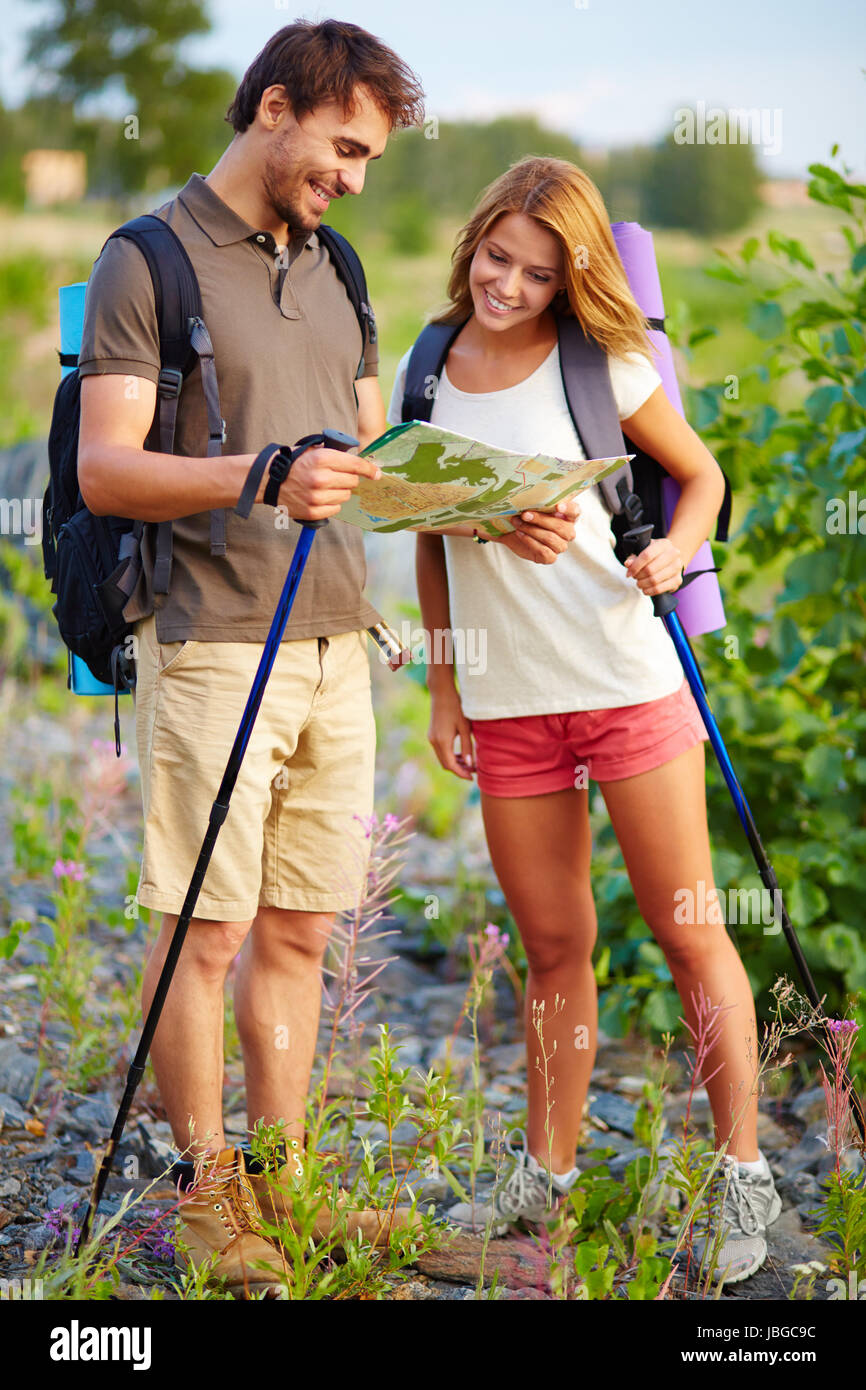 Portrait of young hikers looking at map in the countryside at summer ...