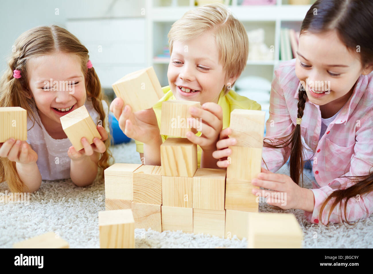Three little friends playing with wooden bricks Stock Photo - Alamy