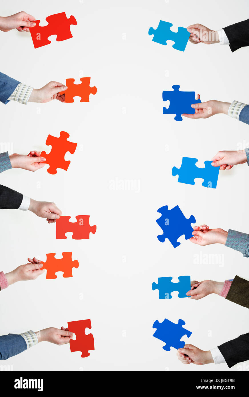 set of red and blue puzzle pieces in opposite sides in people hands on ...