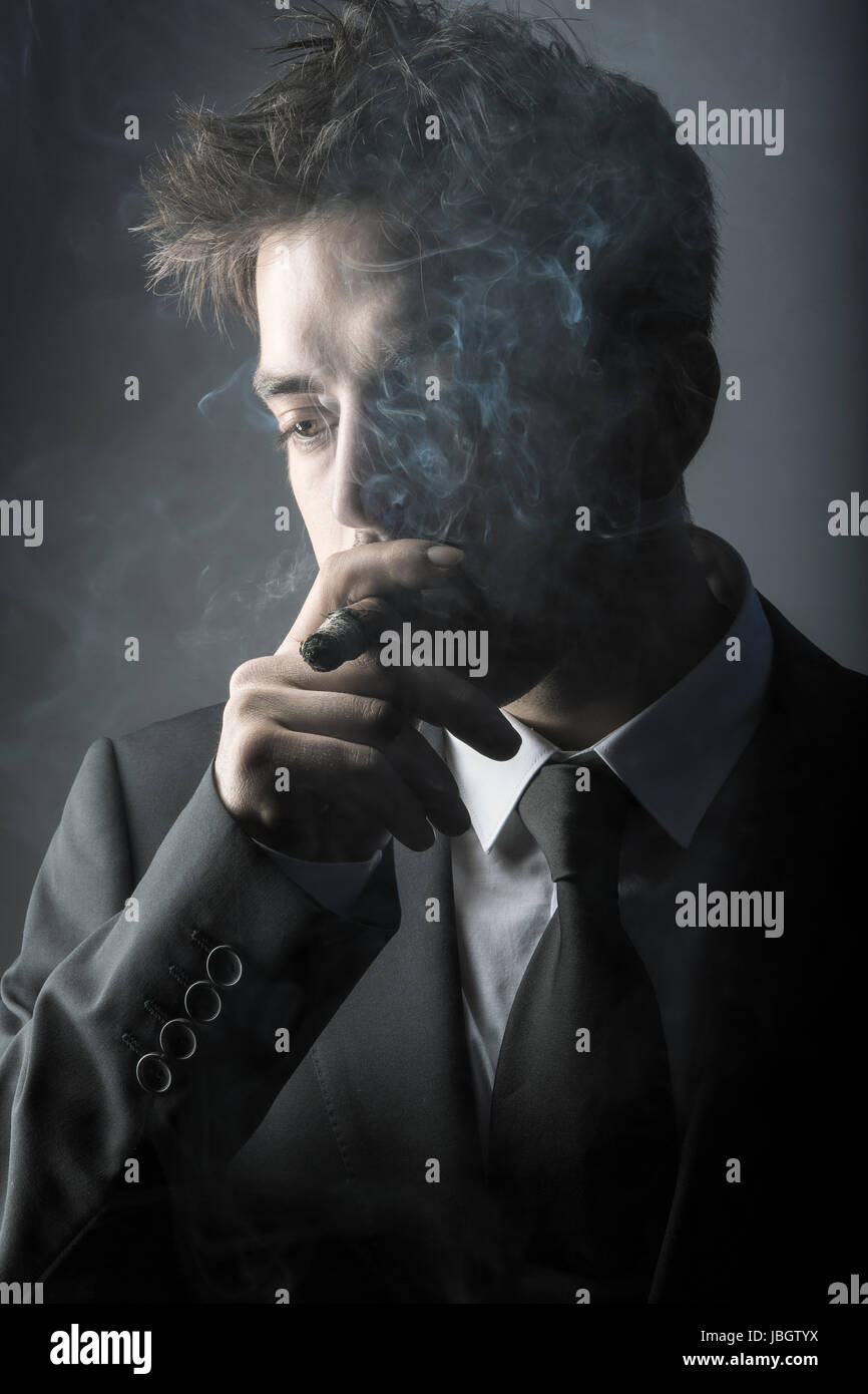 Young stylish man smoking a cigar Stock Photo - Alamy