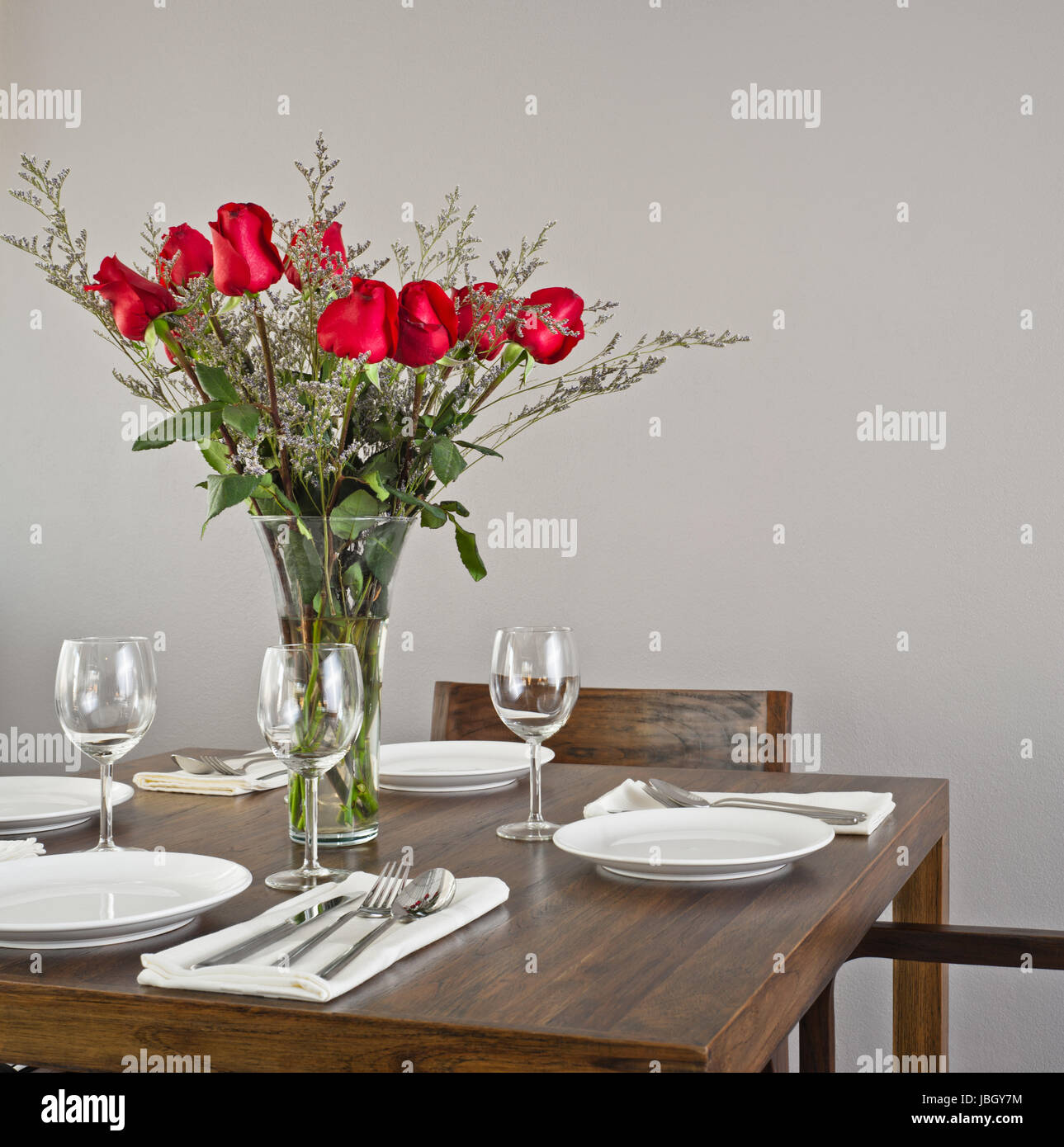 Dinner table setup for four with red roses Stock Photo - Alamy