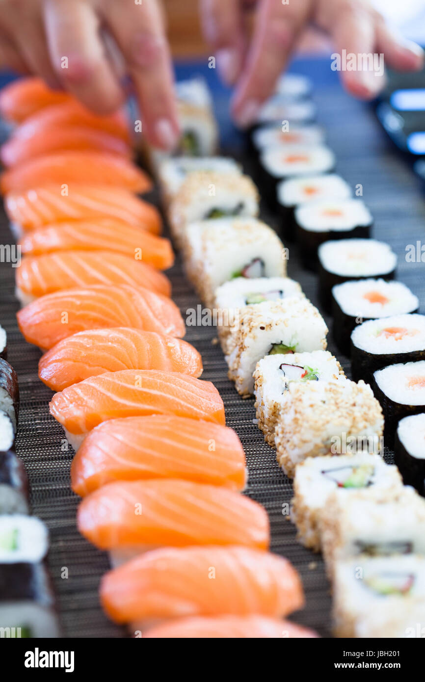 Closeup of healthy freshly prepared sushi rolls with fingers in ...