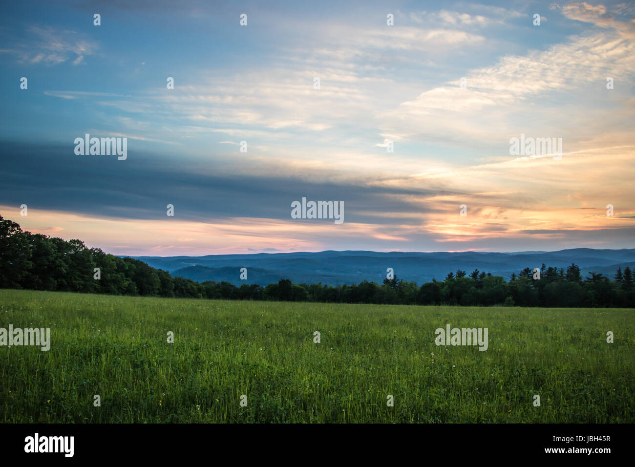 Beautiful Sunset over Meadow with Mountain View Stock Photo - Alamy