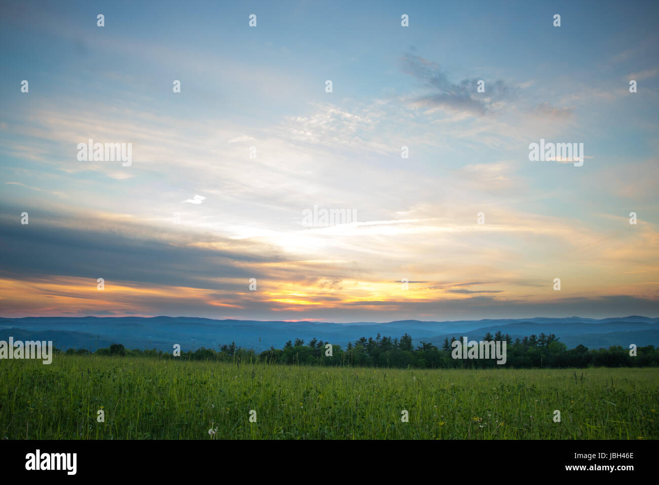 Beautiful Sunset over Meadow with Mountain View Stock Photo - Alamy