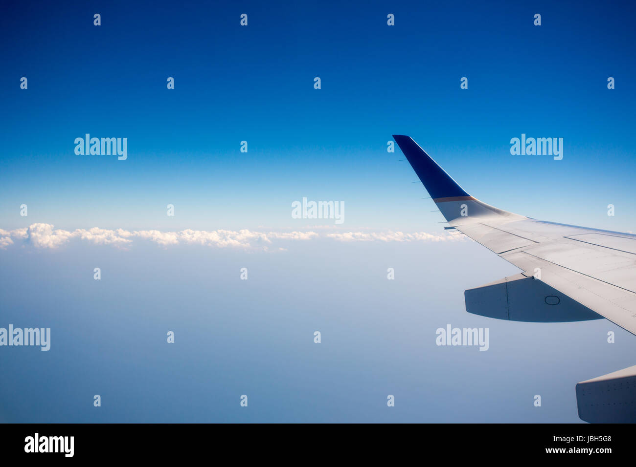 View of jet plane wing with crystal blue sky in the background and ...