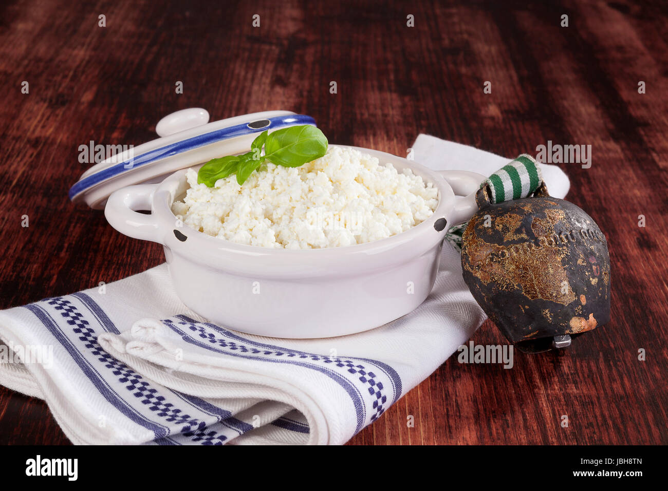 Delicious curd with traditional cow bell on dark wooden background ...