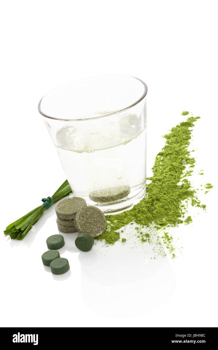 Green effervescent tablet dissolving in glass of water. Spirulina ...