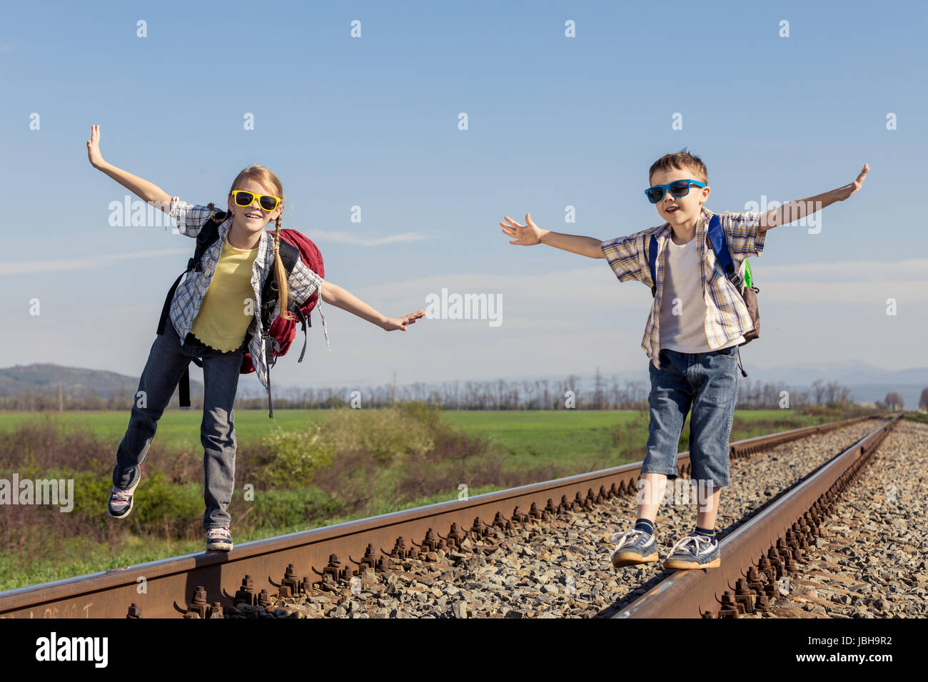 Happy brother and sister walking on the railway at the day time. People ...