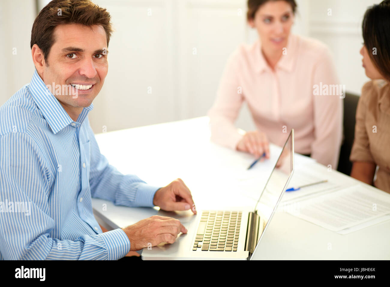 Portrait of handsome professional guy smiling at you while working on ...