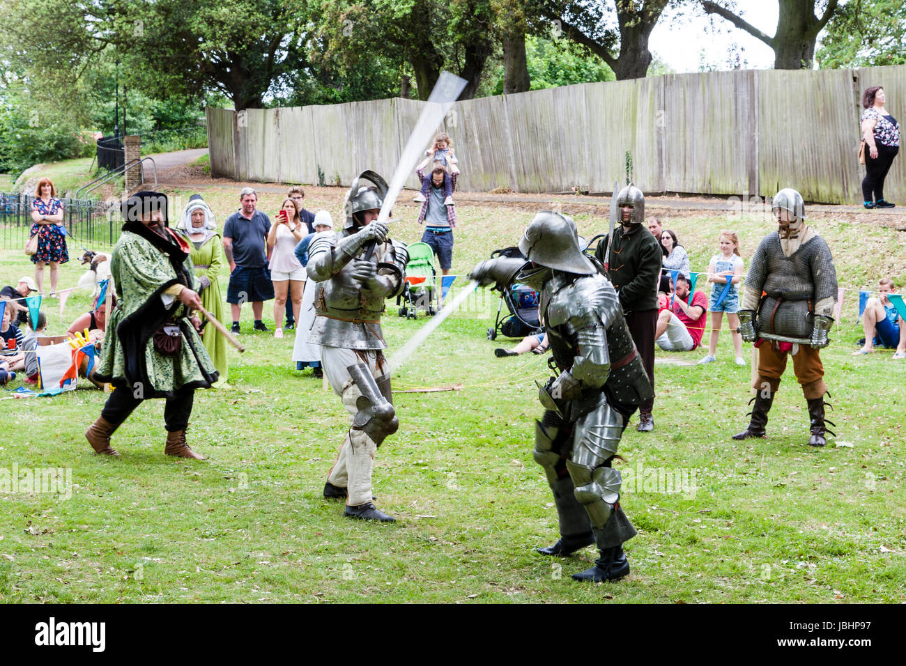 Medieval re-enactment event. Knights in armour fighting in small roped ...
