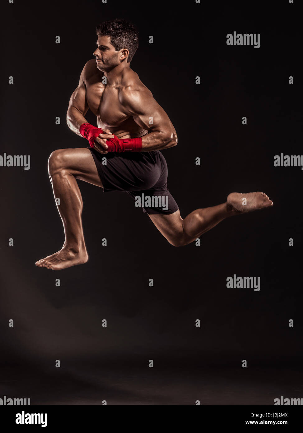 Portrait of a muscular man practicing body combat against a dark ...