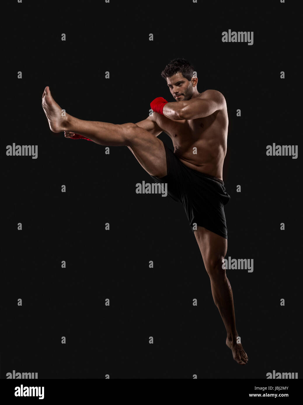 Portrait of a muscular man practicing body combat against a dark ...