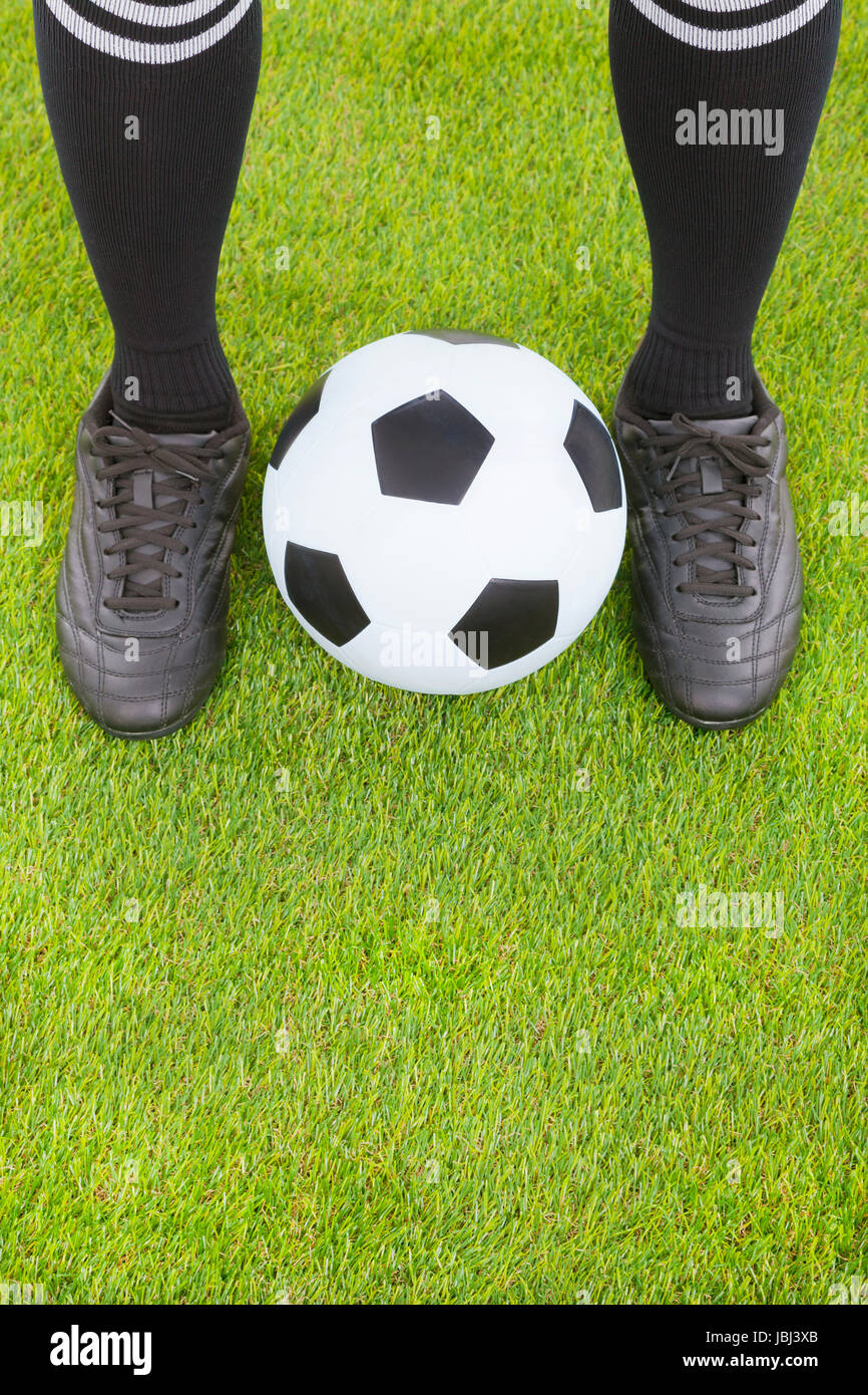 Soccer player's feet and football on field Stock Photo - Alamy