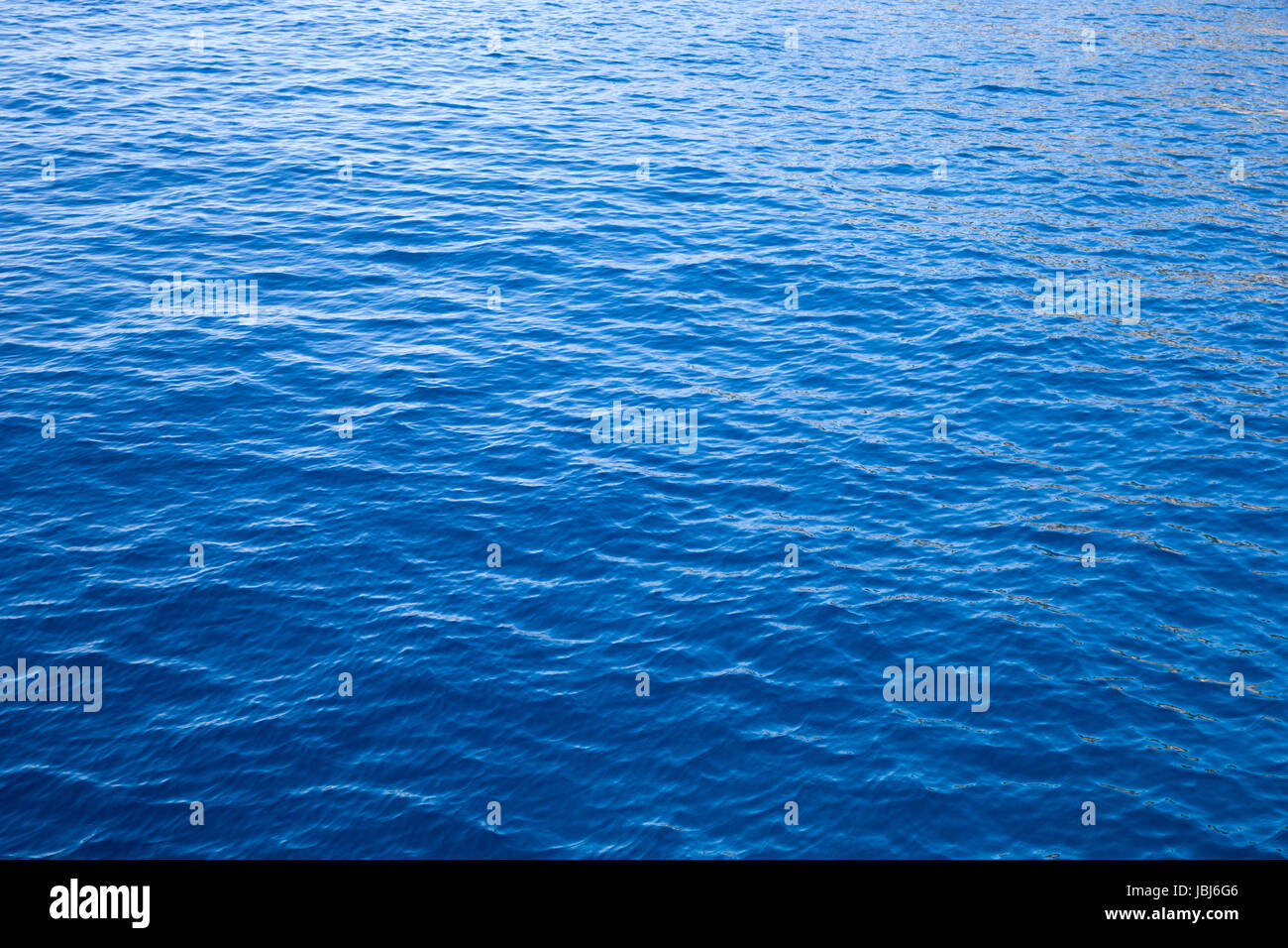 Blue water with sun reflections Stock Photo - Alamy