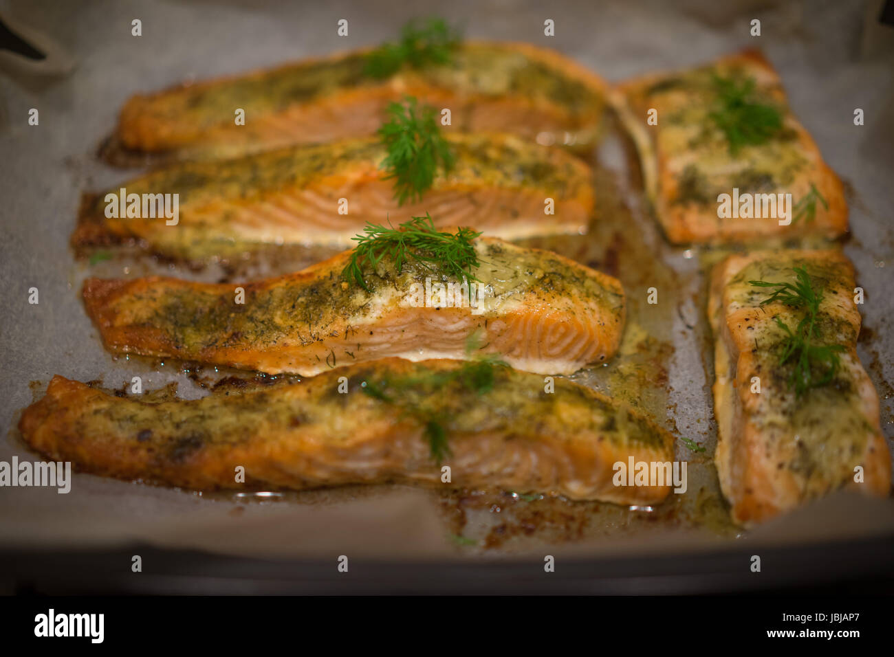 Seasoned savory fish fillets with a herb garnish cooking in a roasting ...