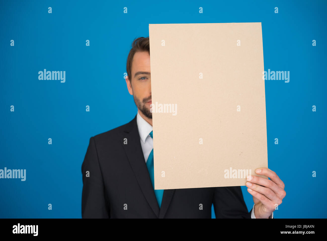 handsome Businessman holding blank poster on blue Stock Photo - Alamy