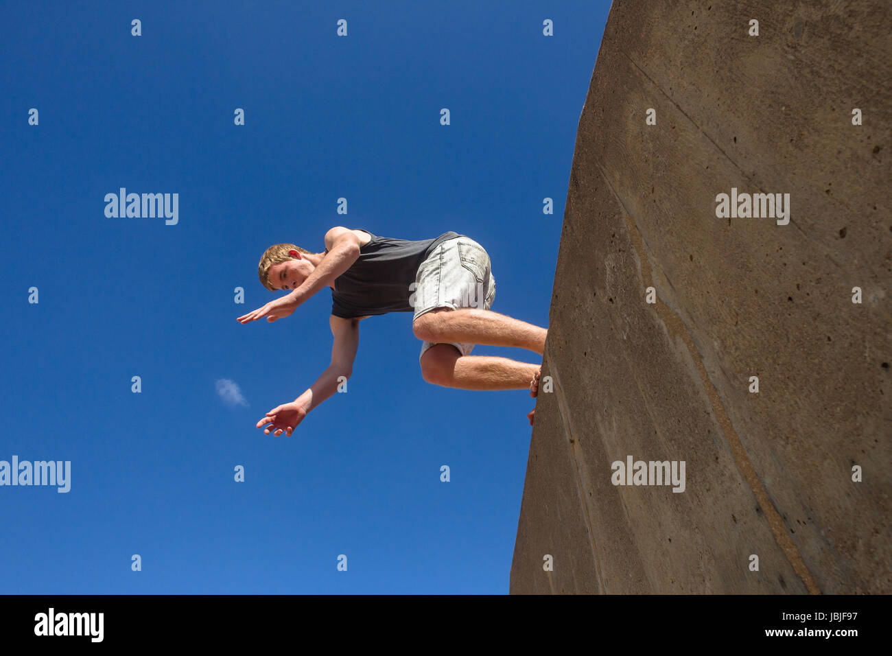 Teen boy jumping off wall into summersault flips on beach Stock Photo ...