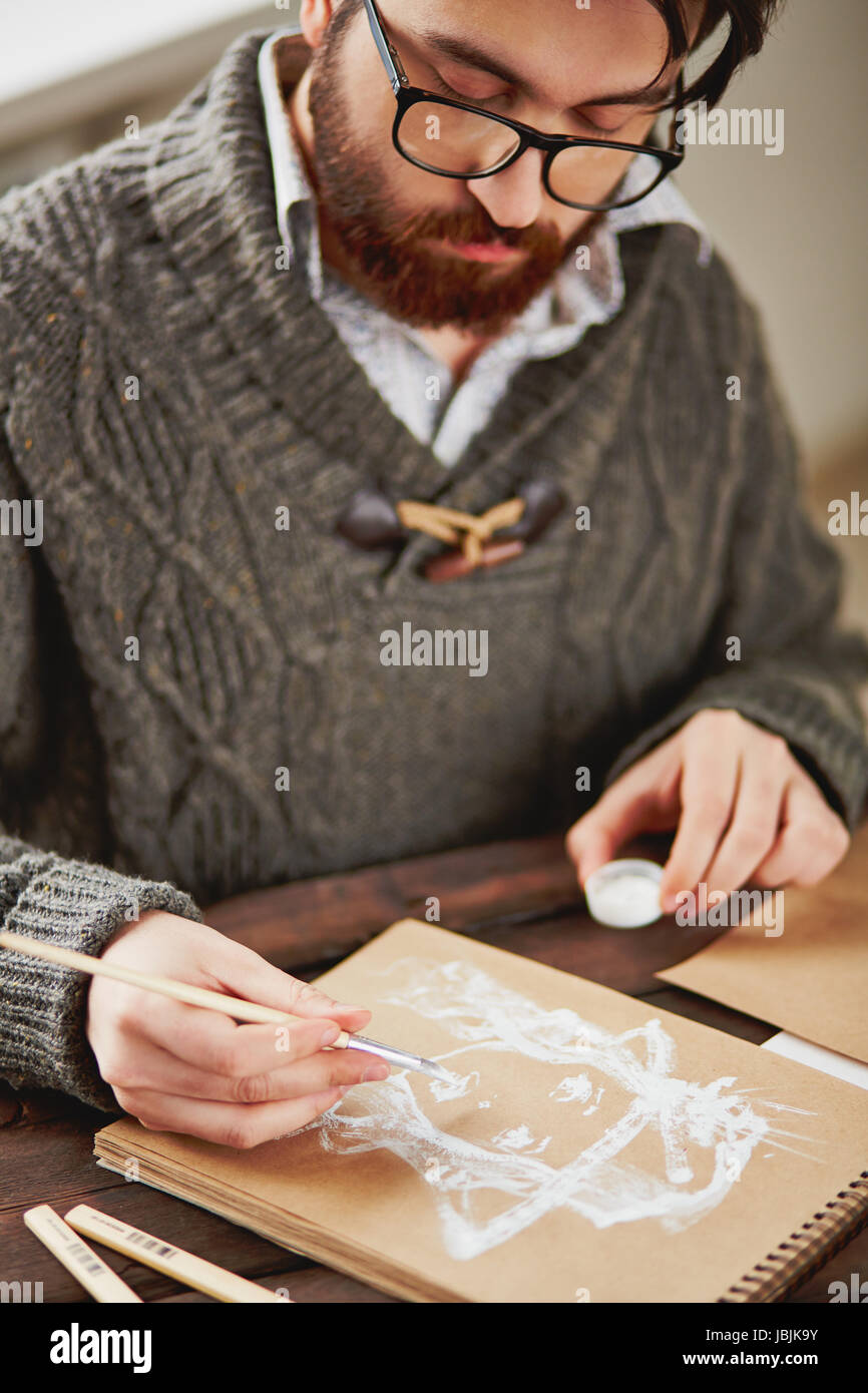 Image of serious young man in sweater drawing Stock Photo - Alamy