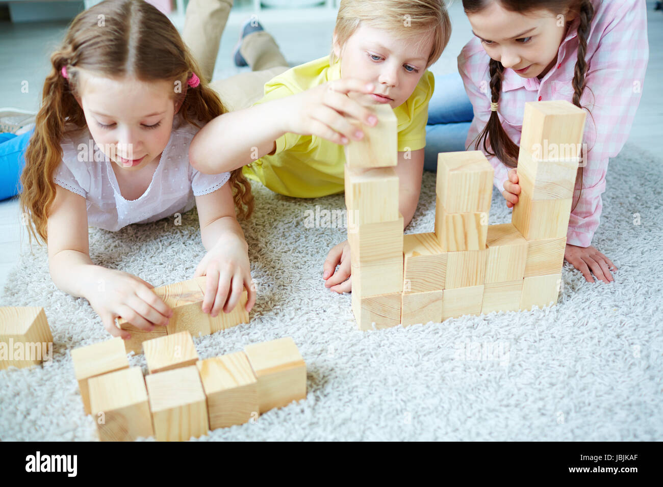 Three little friends playing with wooden bricks Stock Photo - Alamy