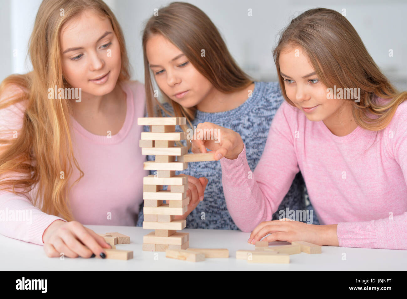 Three teenage girls playing with wooden blocks Stock Photo - Alamy
