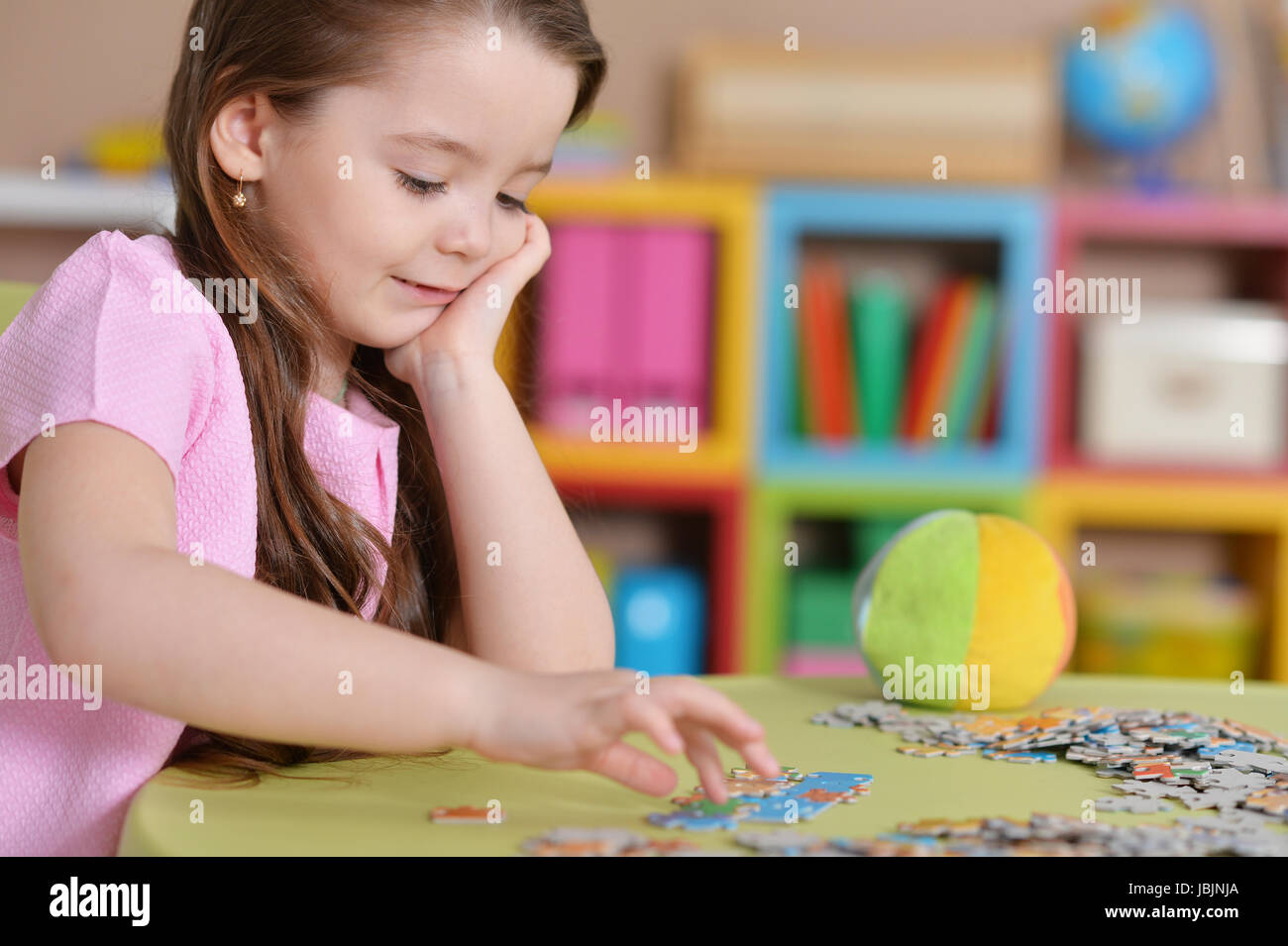 Portrait of a cute little girl collecting puzzles Stock Photo - Alamy