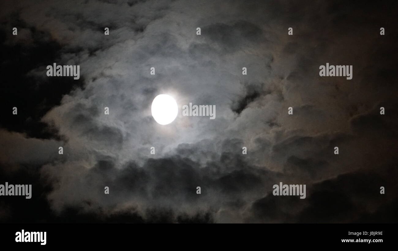 Full moon behind clouds at night . black background Stock Photo - Alamy