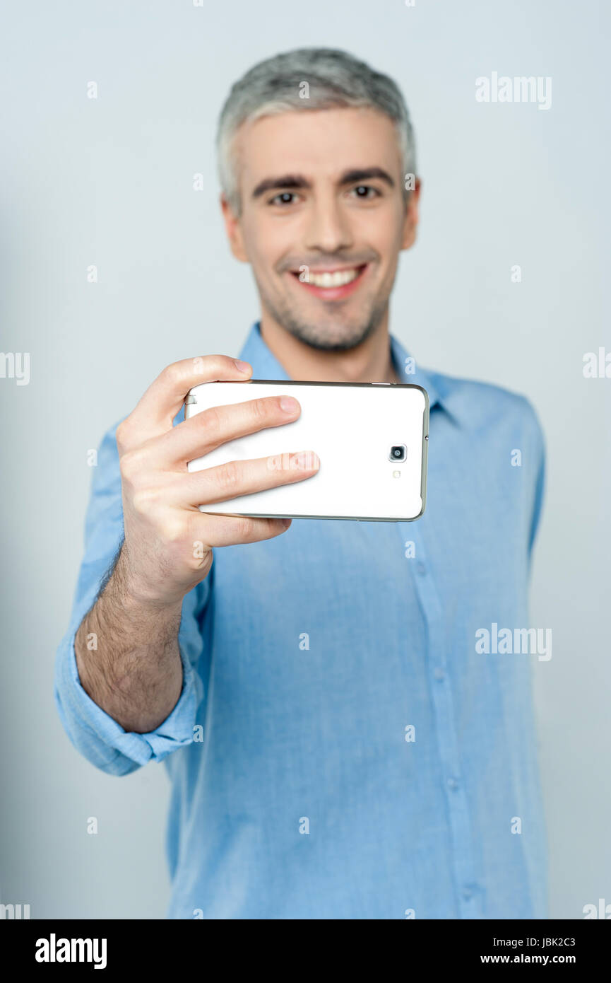 Casual young man taking a picture with his phone Stock Photo - Alamy