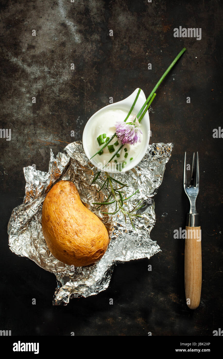 Baked jacket potato cooked over a summer barbecue in aluminium foil ...