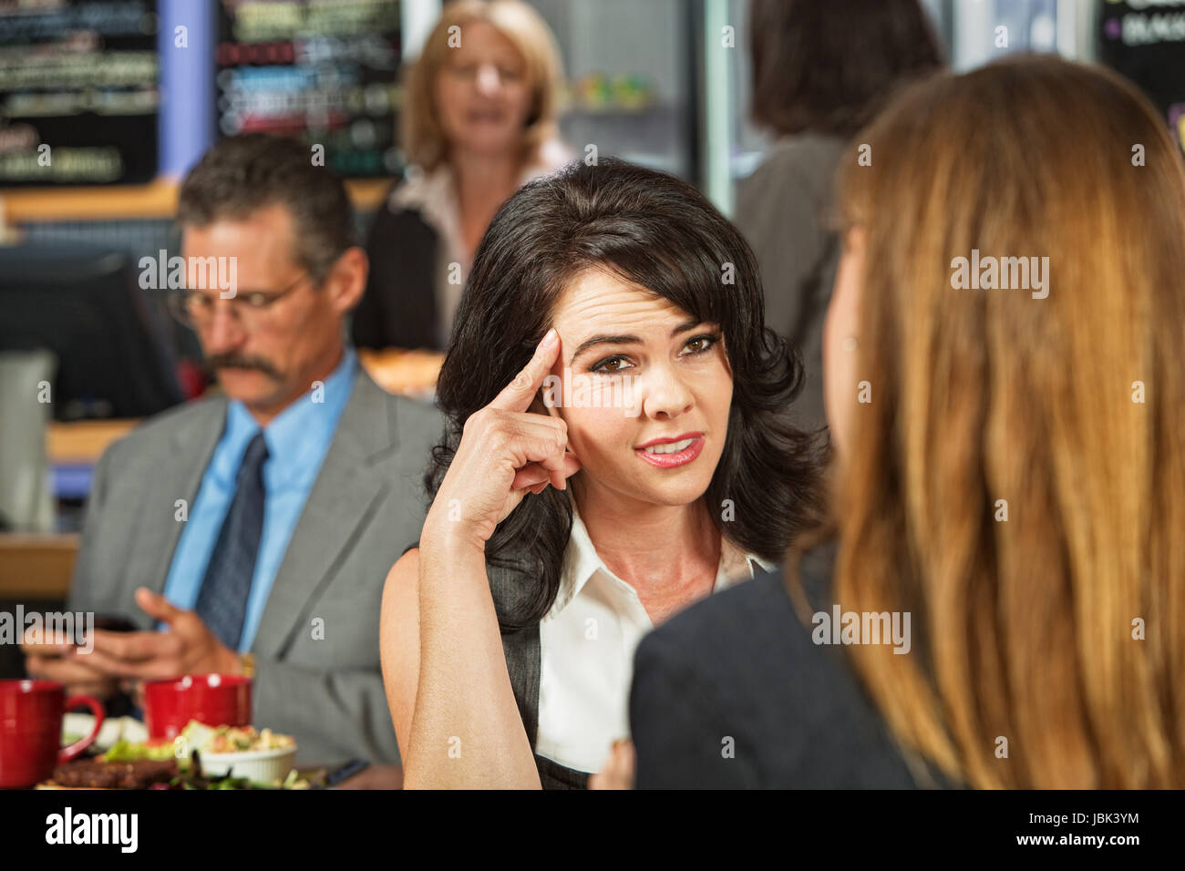 Skeptical woman with friend in coffee house Stock Photo - Alamy