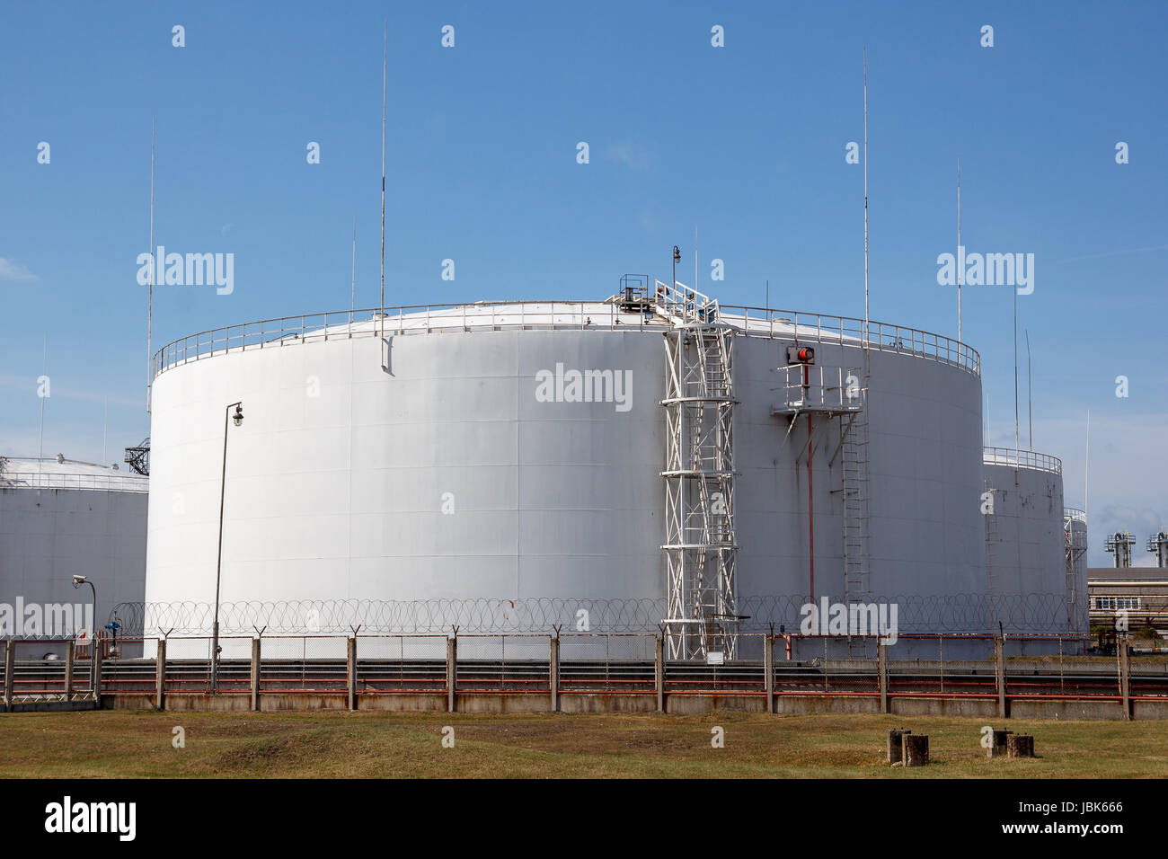 multiple white big oil storage tanks with a fence around them Stock ...