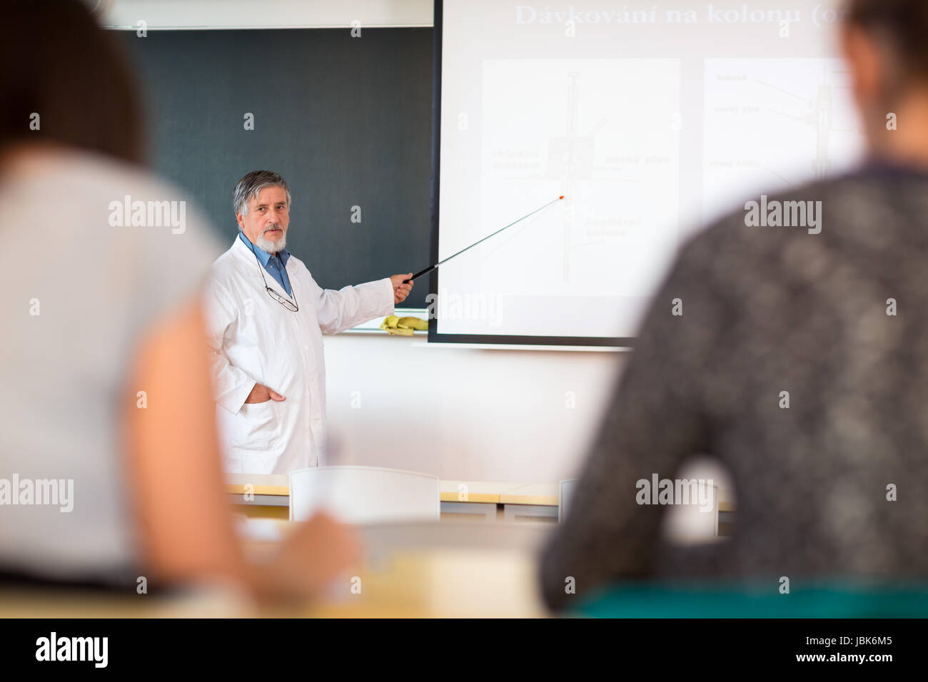 Senior chemistry professor giving a lecture in front of classroom full ...