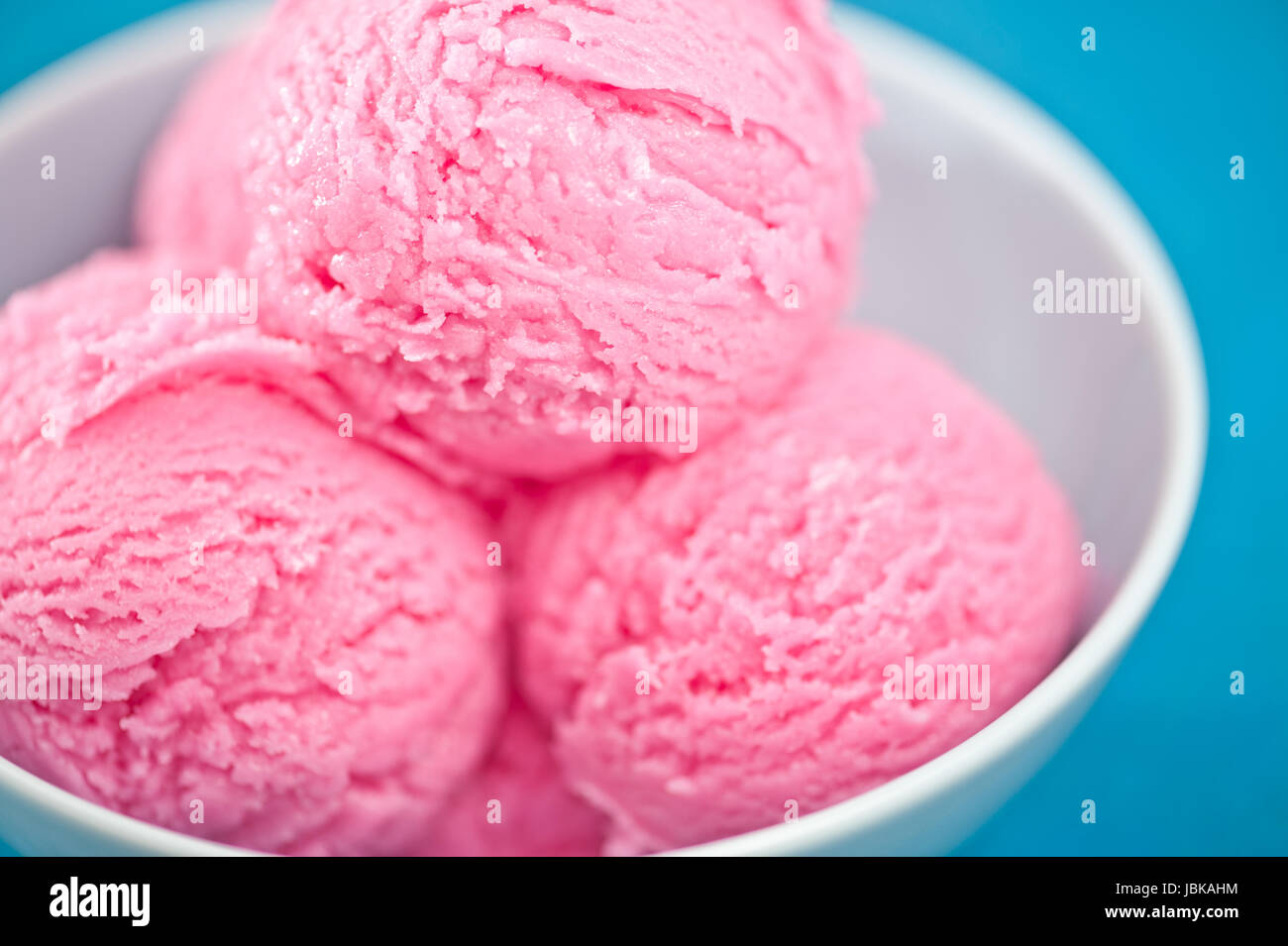 Raspberry ice cream cup over bBLUE background Stock Photo - Alamy