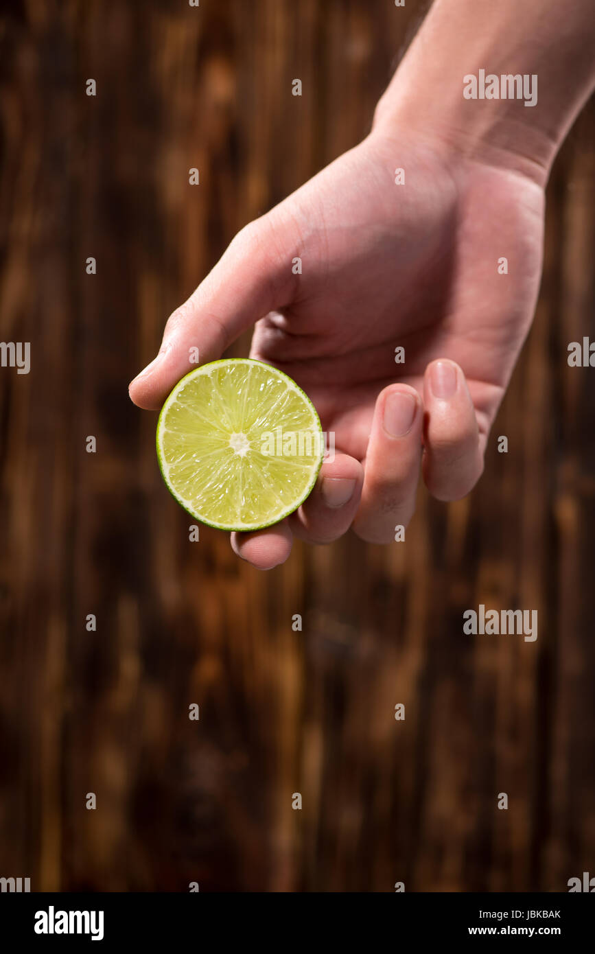 Hand squeeze lime with lime drop on dark wooden background Stock Photo ...
