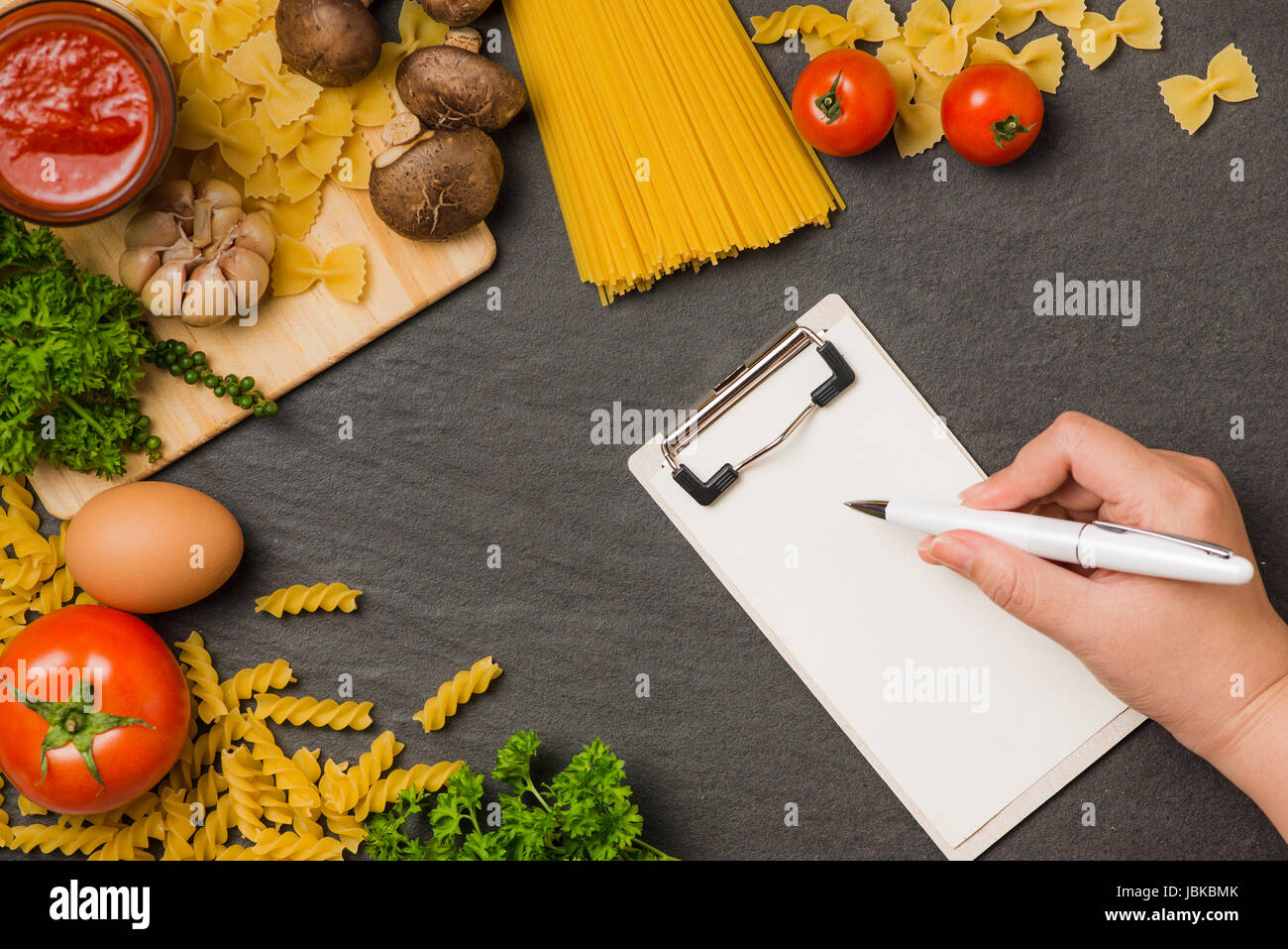 Italian spaghetti photo recipe. Hand with pen writting on blank paper ...