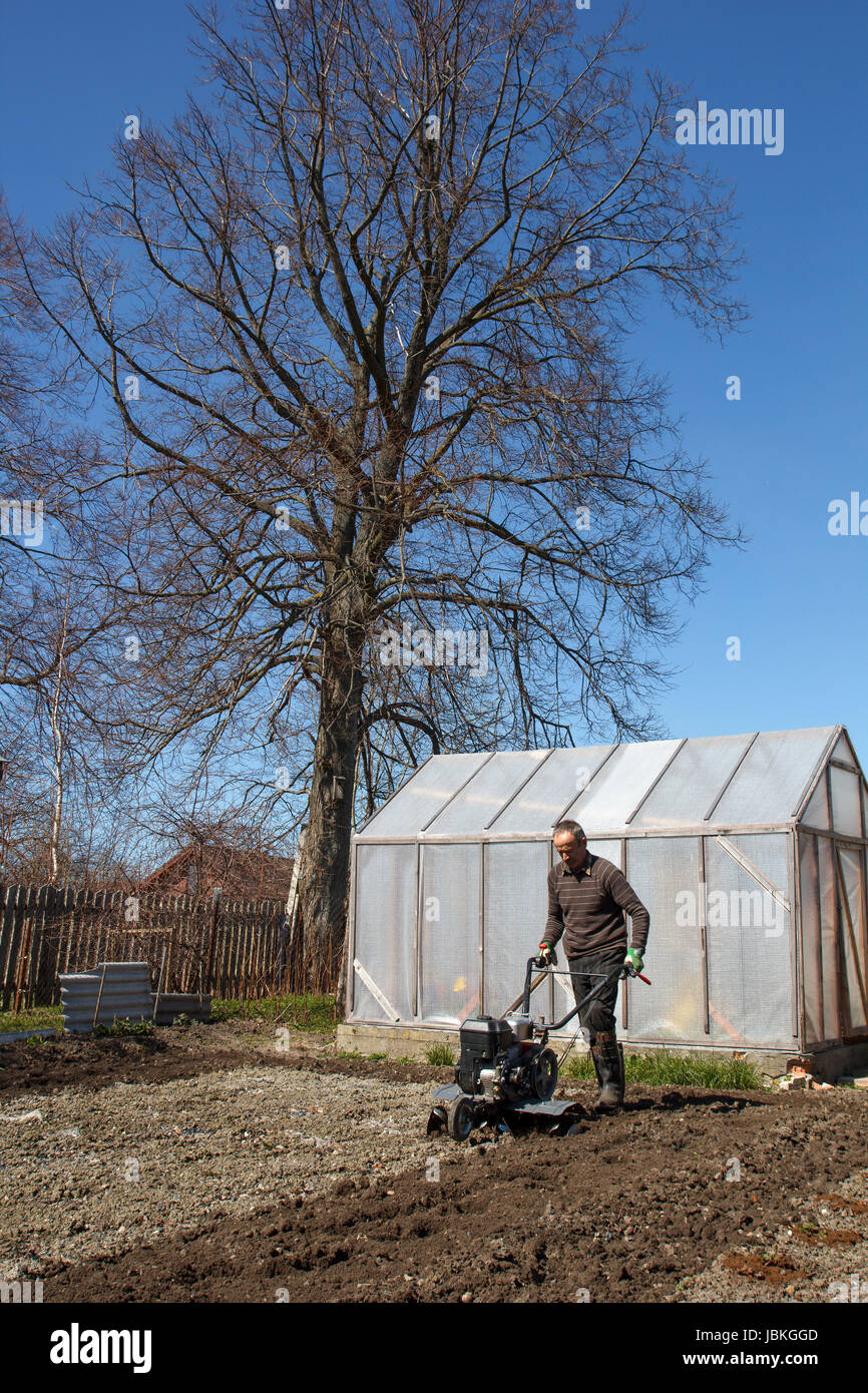 Spring Garden work. man working with Garden Tiller Stock Photo - Alamy