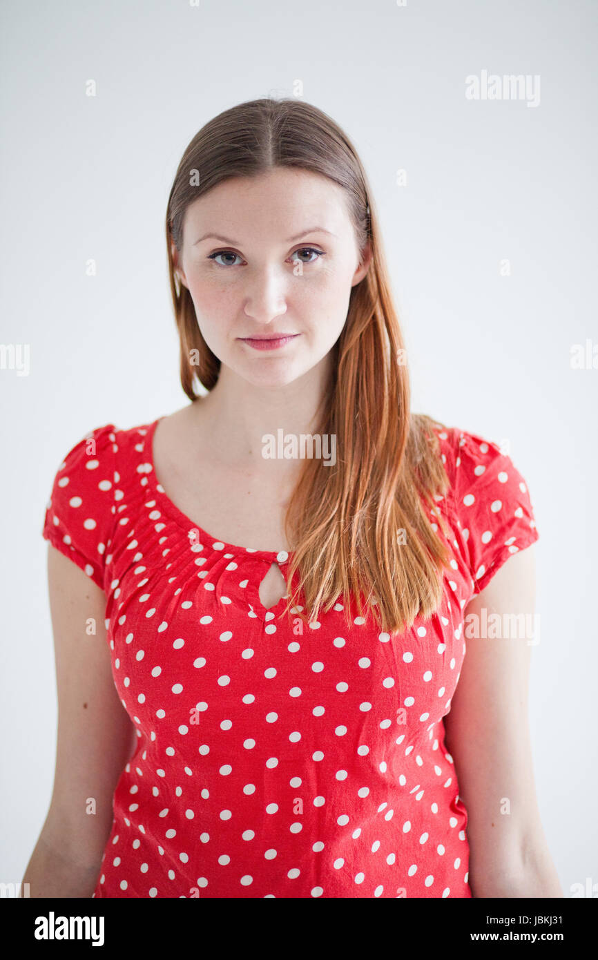 Studio portrait of thoughtful looking attractive woman wearing red ...