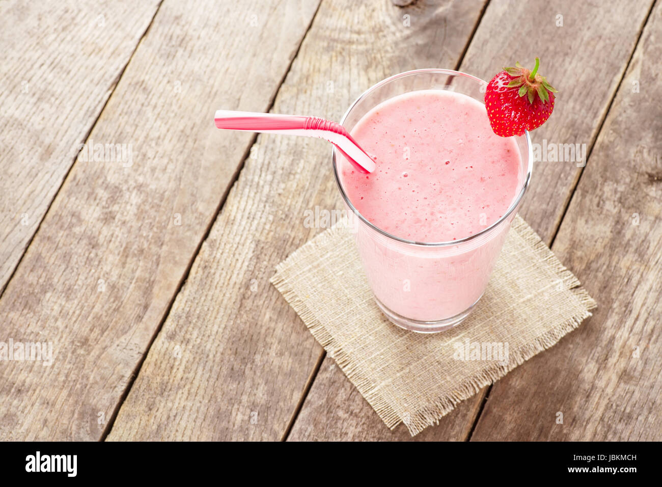 strawberry smoothie with straw in glass on wooden table top view. Pink ...