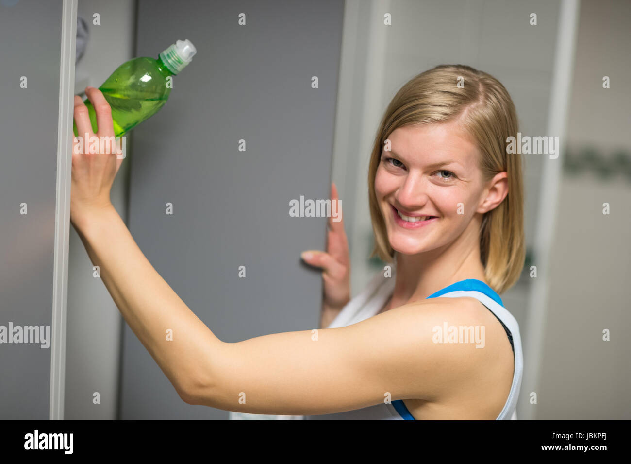 Smiling woman putting water bottle in locker at healthclub Stock Photo ...