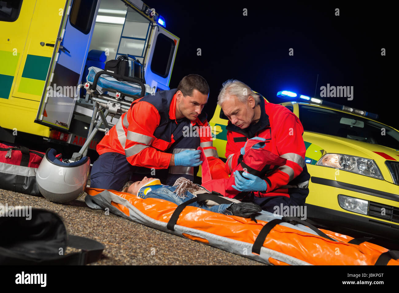 Paramedics giving firstaid to injured motorbike woman driver at night ...