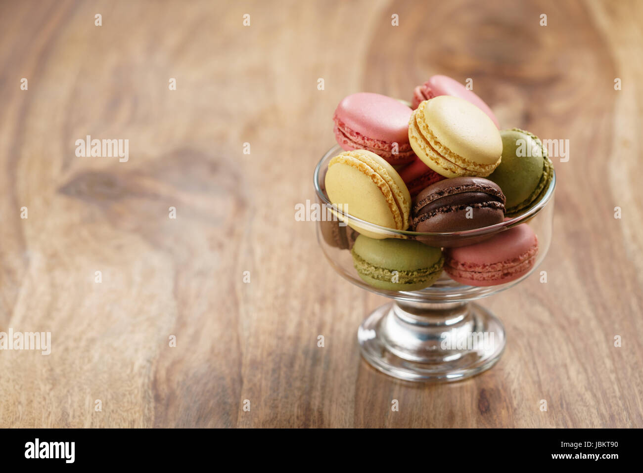 assorted macarons in glass bowl on wood table Stock Photo - Alamy