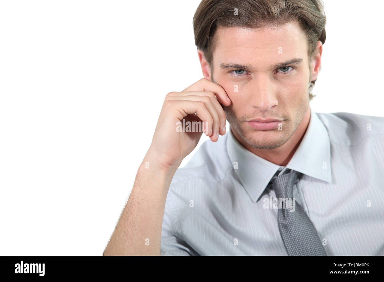 Young businessman with hand to face Stock Photo - Alamy