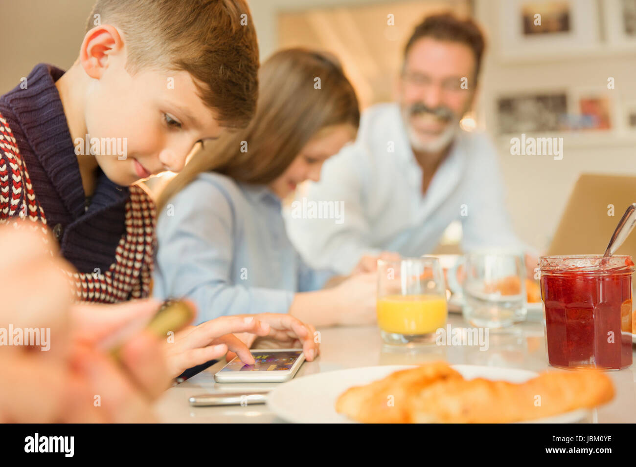 Boy using cell phone at breakfast table Stock Photo - Alamy
