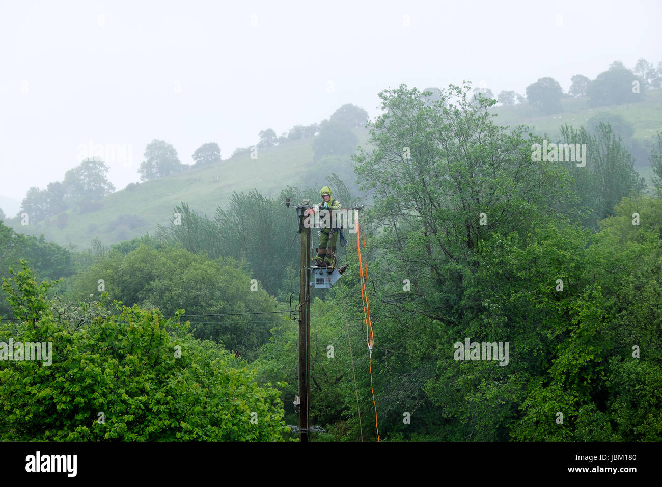 Man working in rainy weather on electricity pole power lines to upgrade ...
