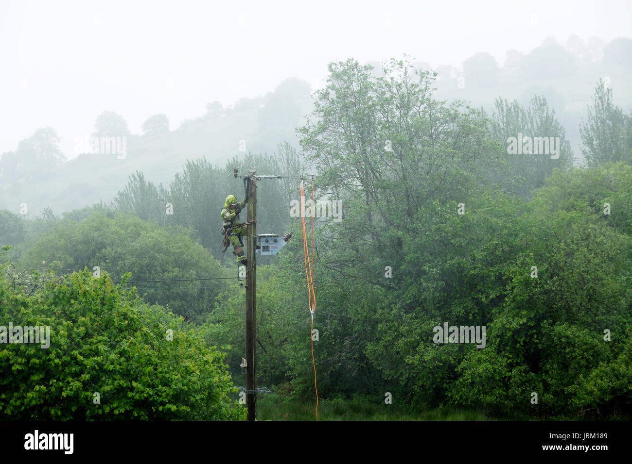 Man working in rainy weather on electricity pole power lines to upgrade ...