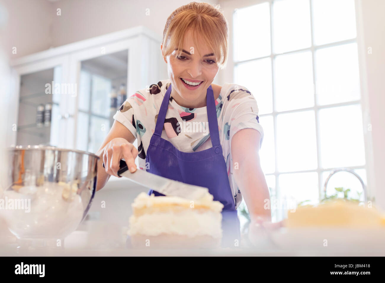 Smiling woman baking, icing layer cake in kitchen Stock Photo - Alamy